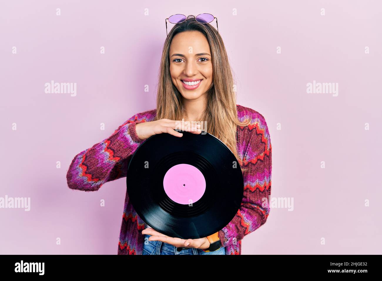 Beautiful hispanic woman wearing hippie style holding vinyl disc ...