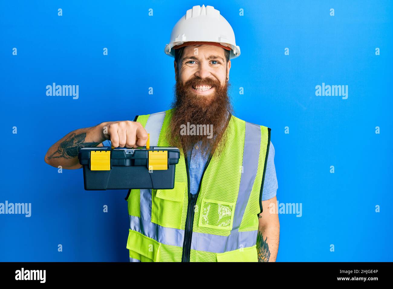 Redhead man with long beard wearing safety helmet and reflective jacket ...