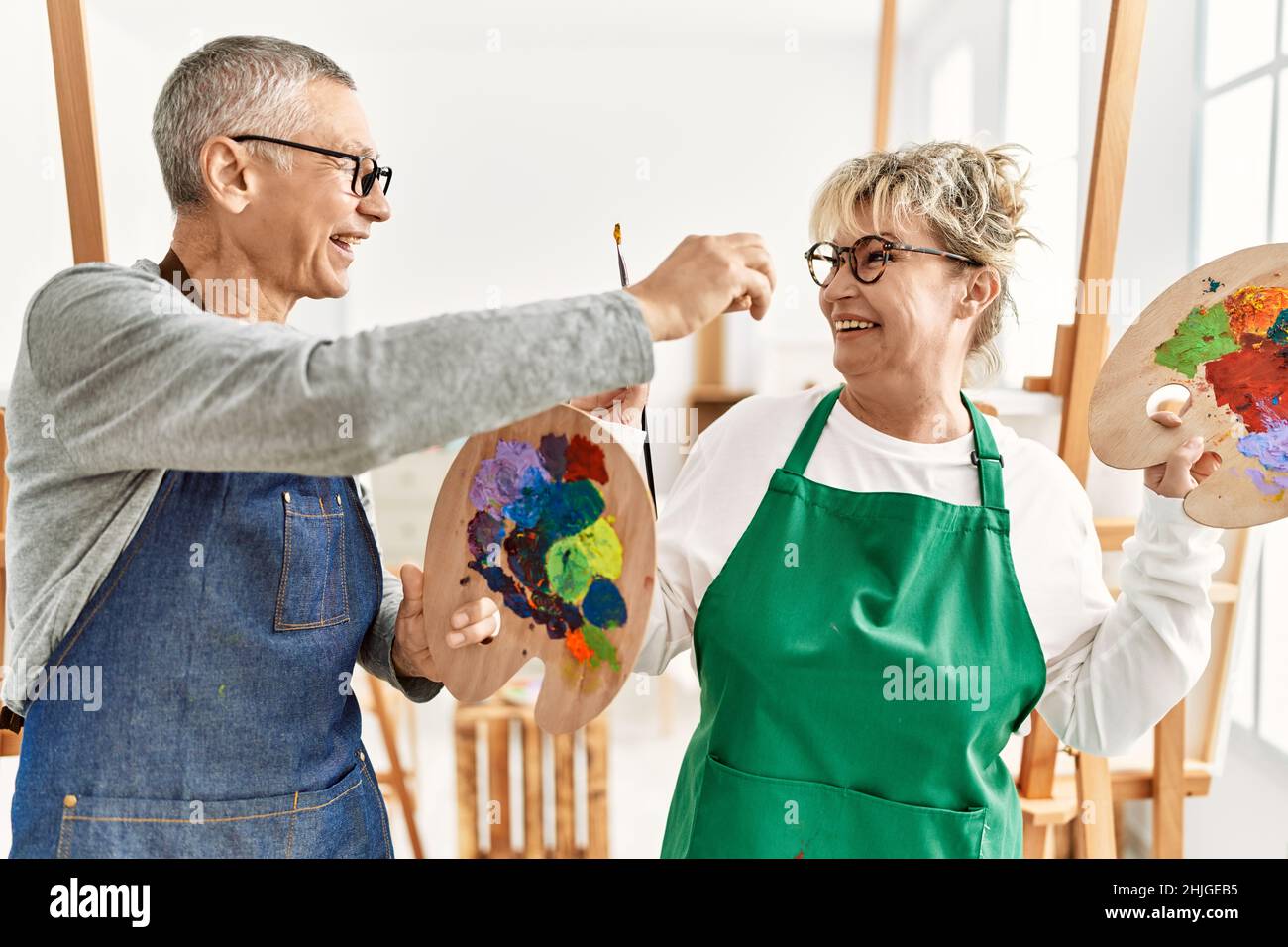 Two senior paint student smiling happy playing with paintbrushes and ...