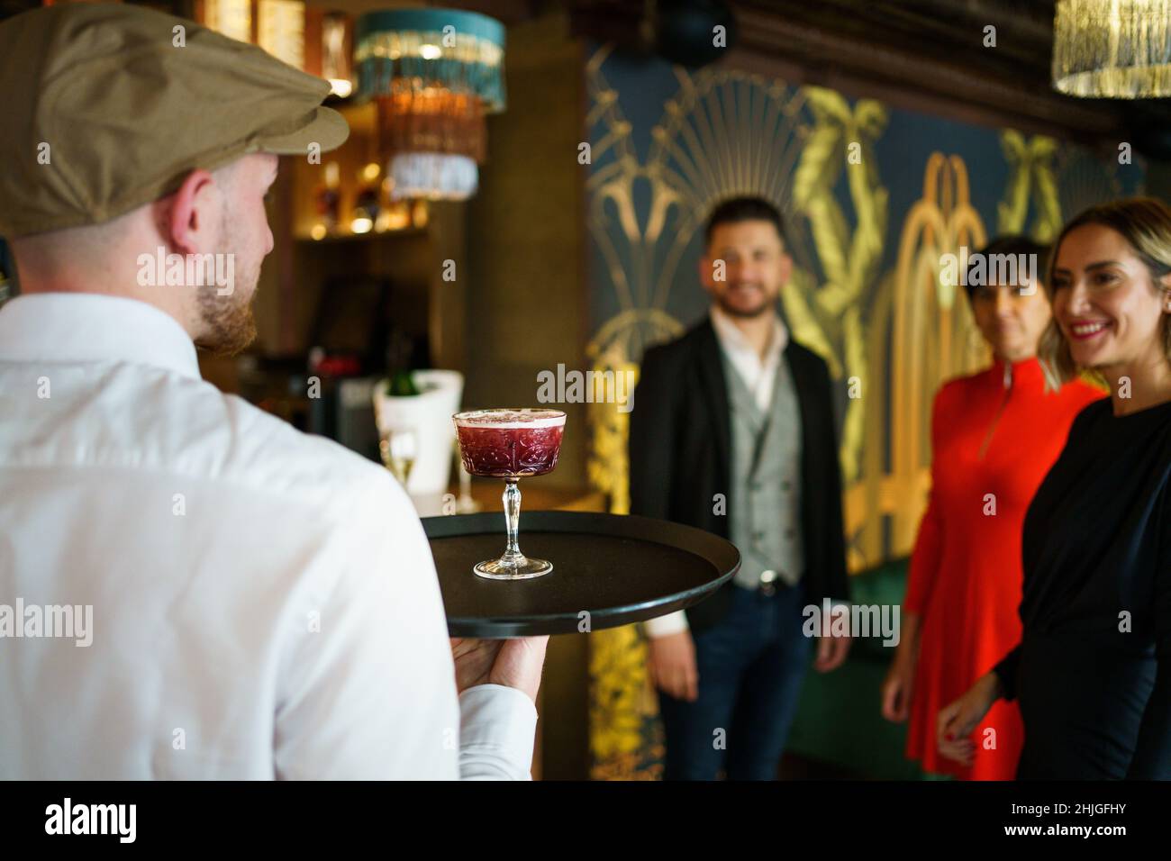 Waiter serving a cocktail for elegant guests in a nice bar Stock Photo ...