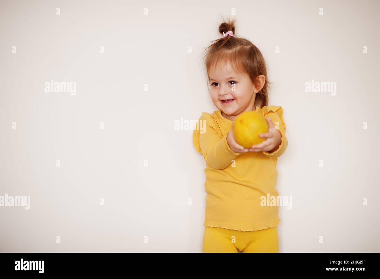 Baby girl in yellow with lemon, isolated background Stock Photo - Alamy