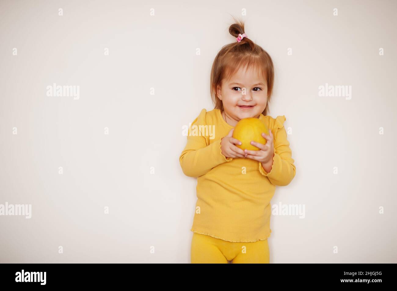 Baby girl in yellow with lemon, isolated background Stock Photo - Alamy