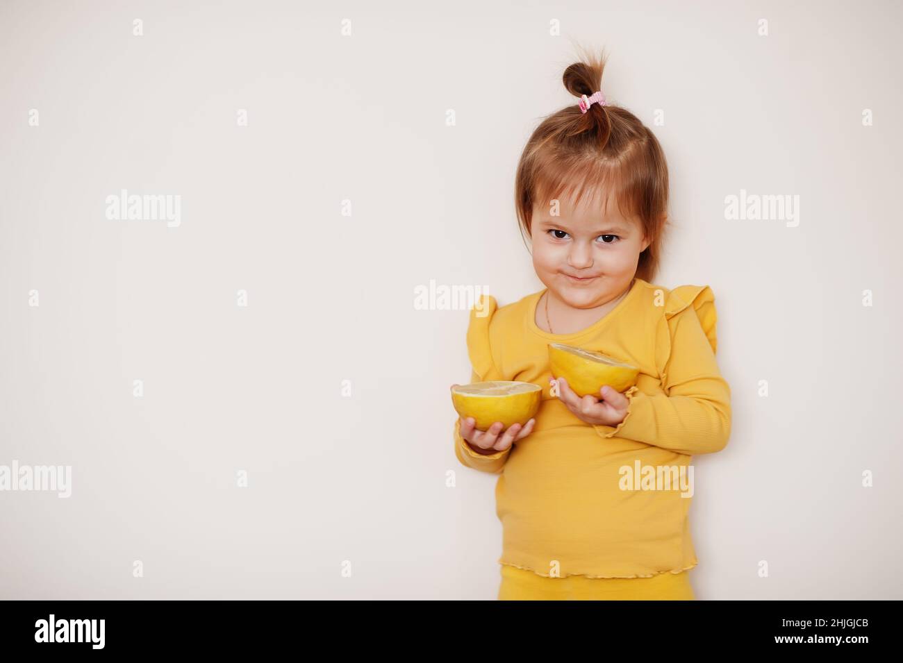 Baby girl in yellow with lemon, isolated background Stock Photo - Alamy