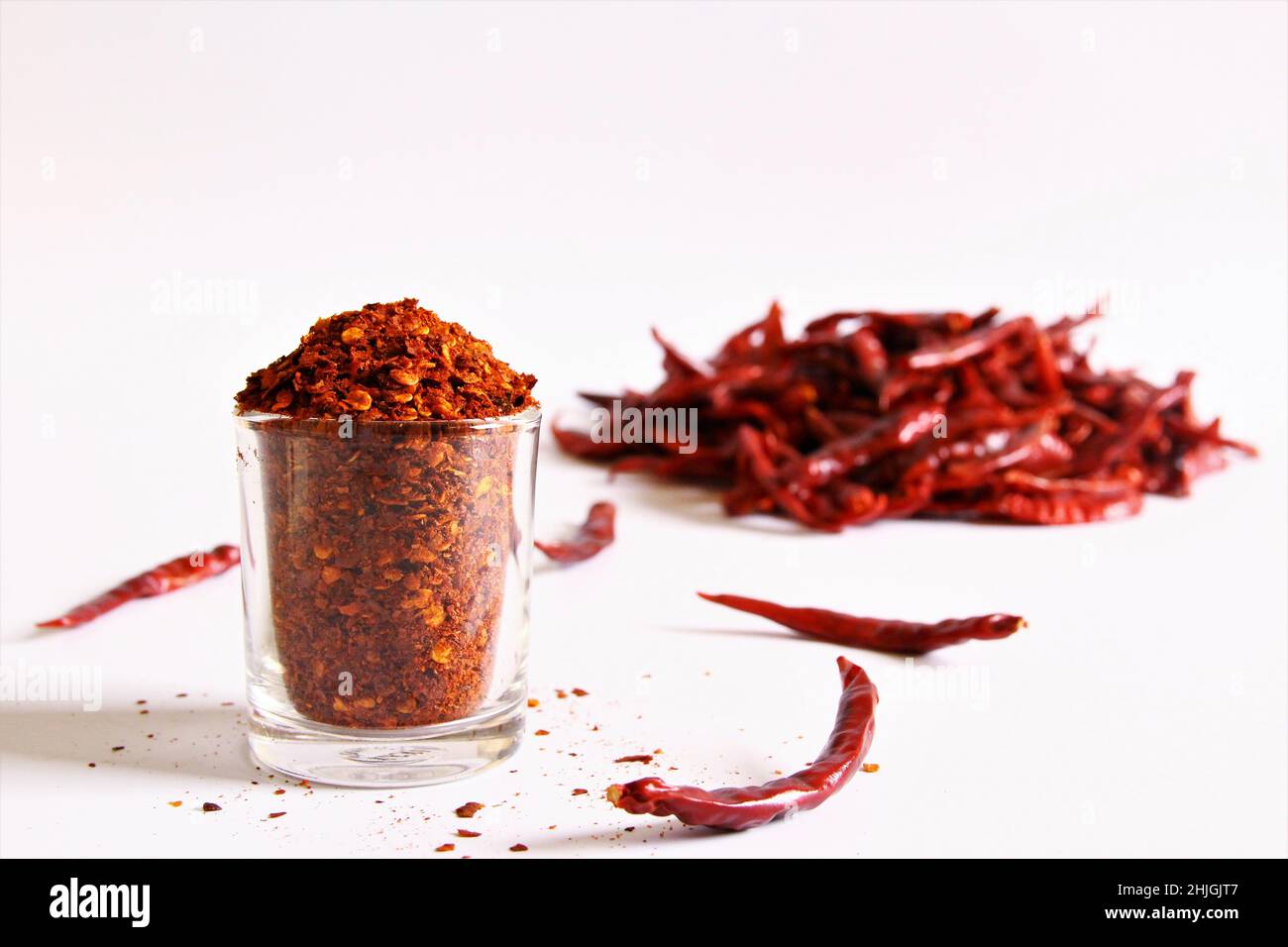 Red chili pepper powder in glass cup photo isolate on white front view ...