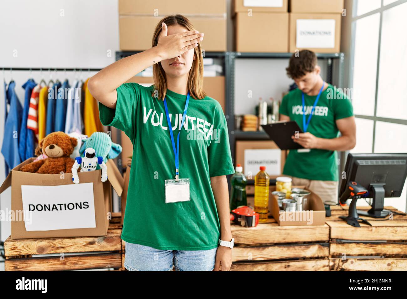 Young blonde girl wearing volunteer t shirt at donation stand covering ...