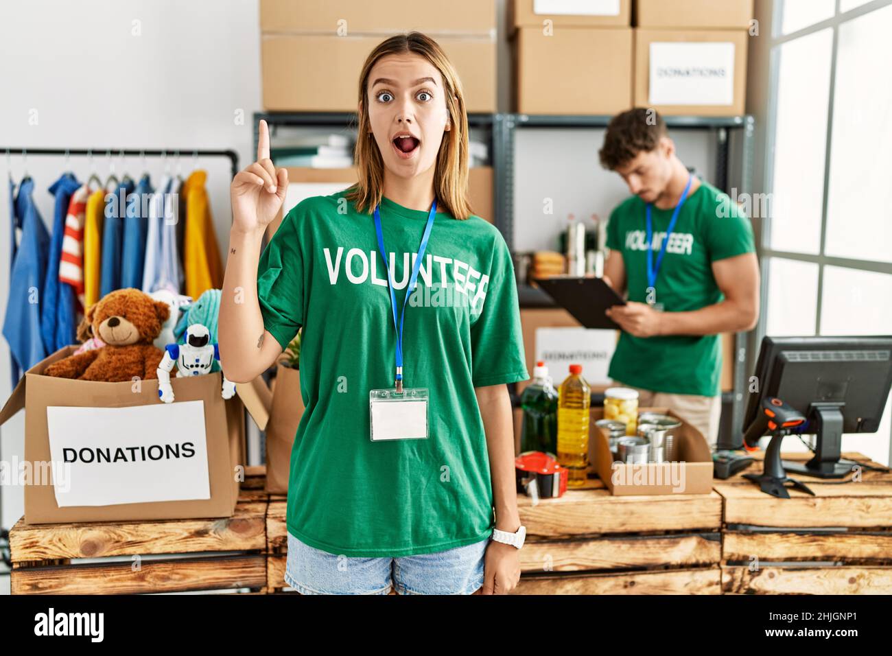 Young blonde girl wearing volunteer t shirt at donation stand pointing ...