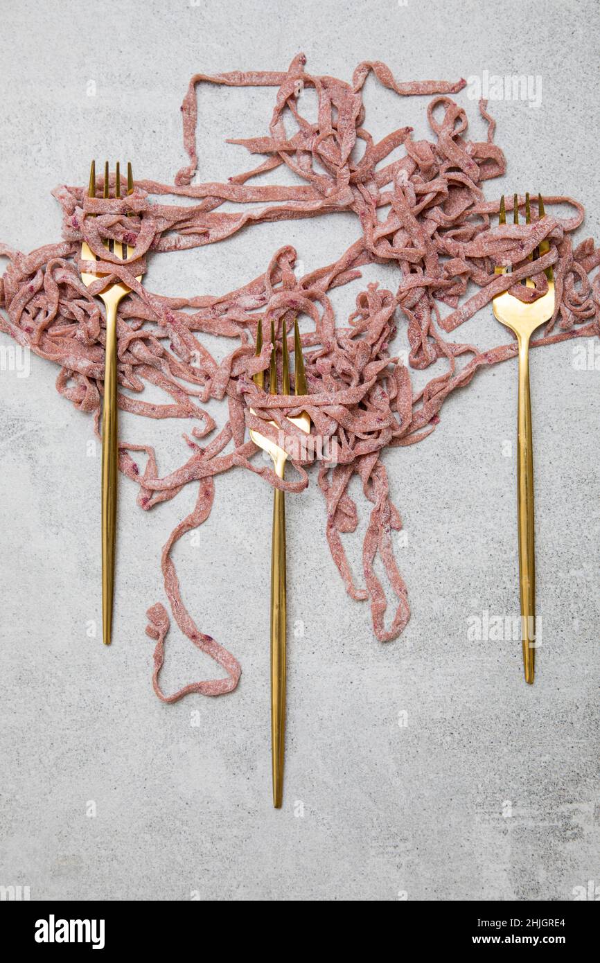 beetroot pasta, with golden forks on a slate background Stock Photo - Alamy