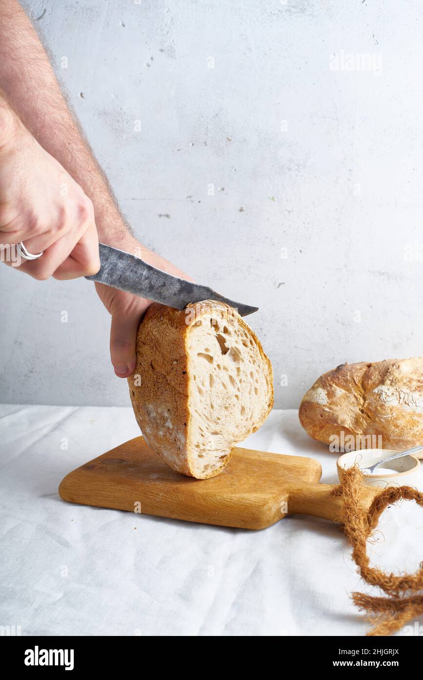 Male hands cutting a loaf of sourdough bread Stock Photo - Alamy