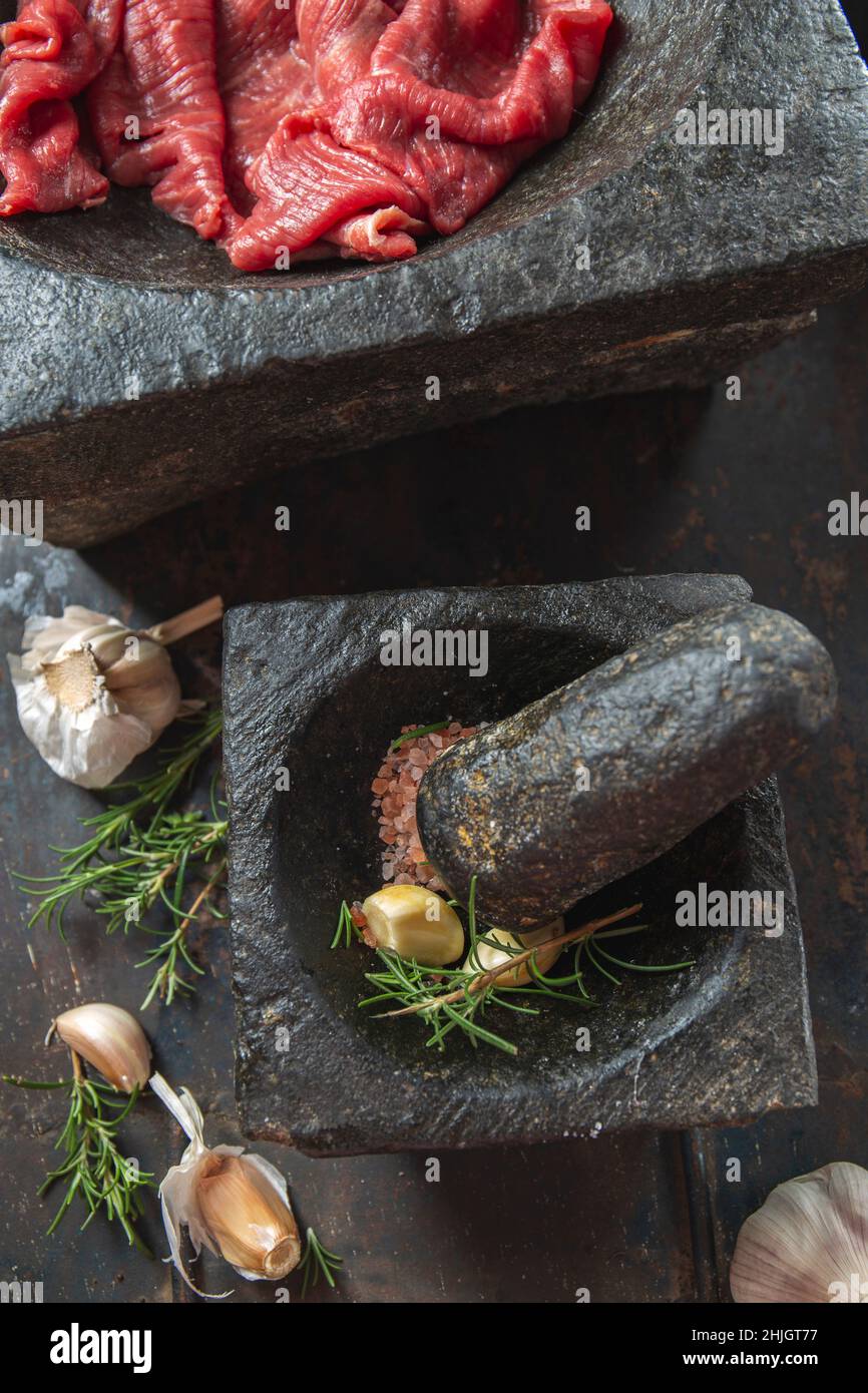 Raw beef fillet on black stone plate and mortar with herbs. Black ...