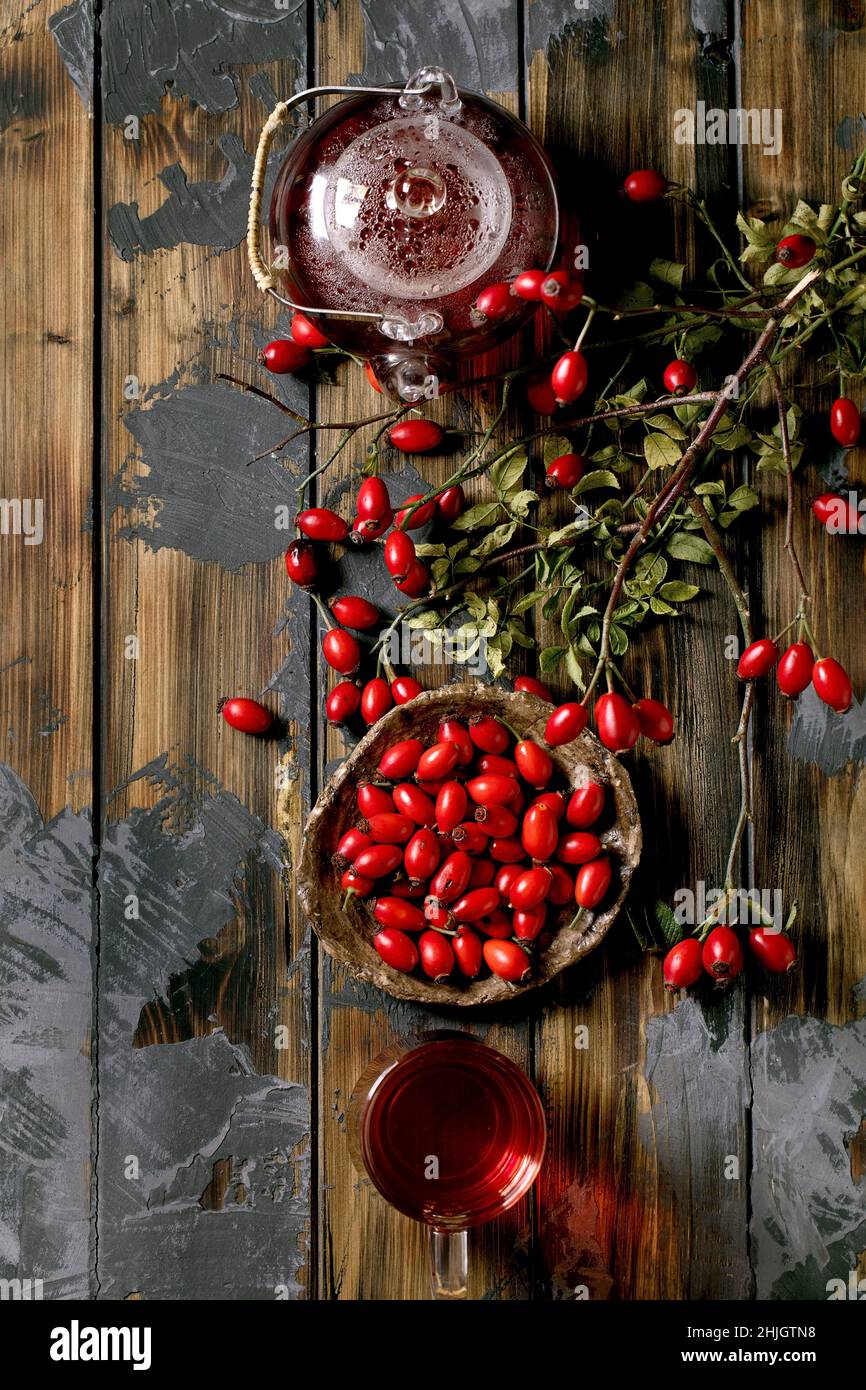 Rose hip berries herbal tea in glass teapot and cup standing on old ...