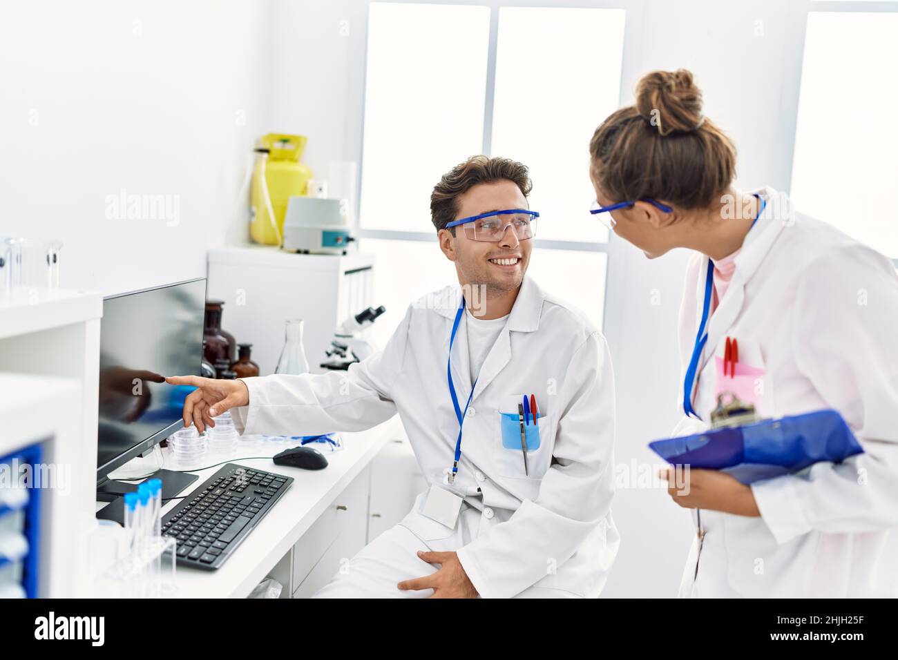 Man and woman wearing scientist uniform using computer working at ...