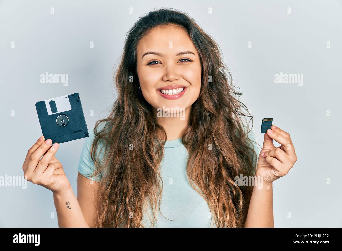 Young hispanic girl holding floppy disk and sdxc card smiling with a ...