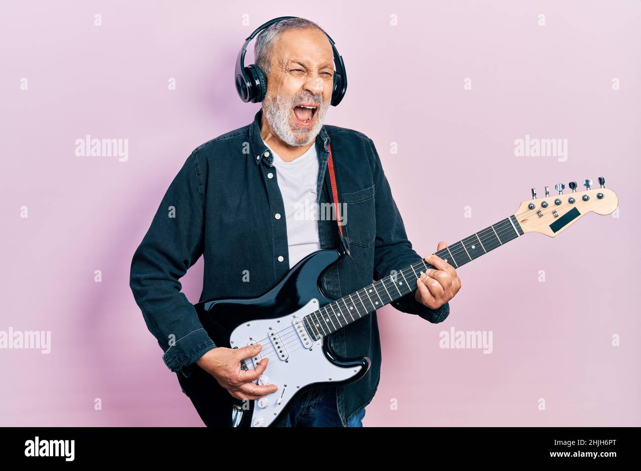 Handsome senior man with beard playing electric guitar angry and mad ...