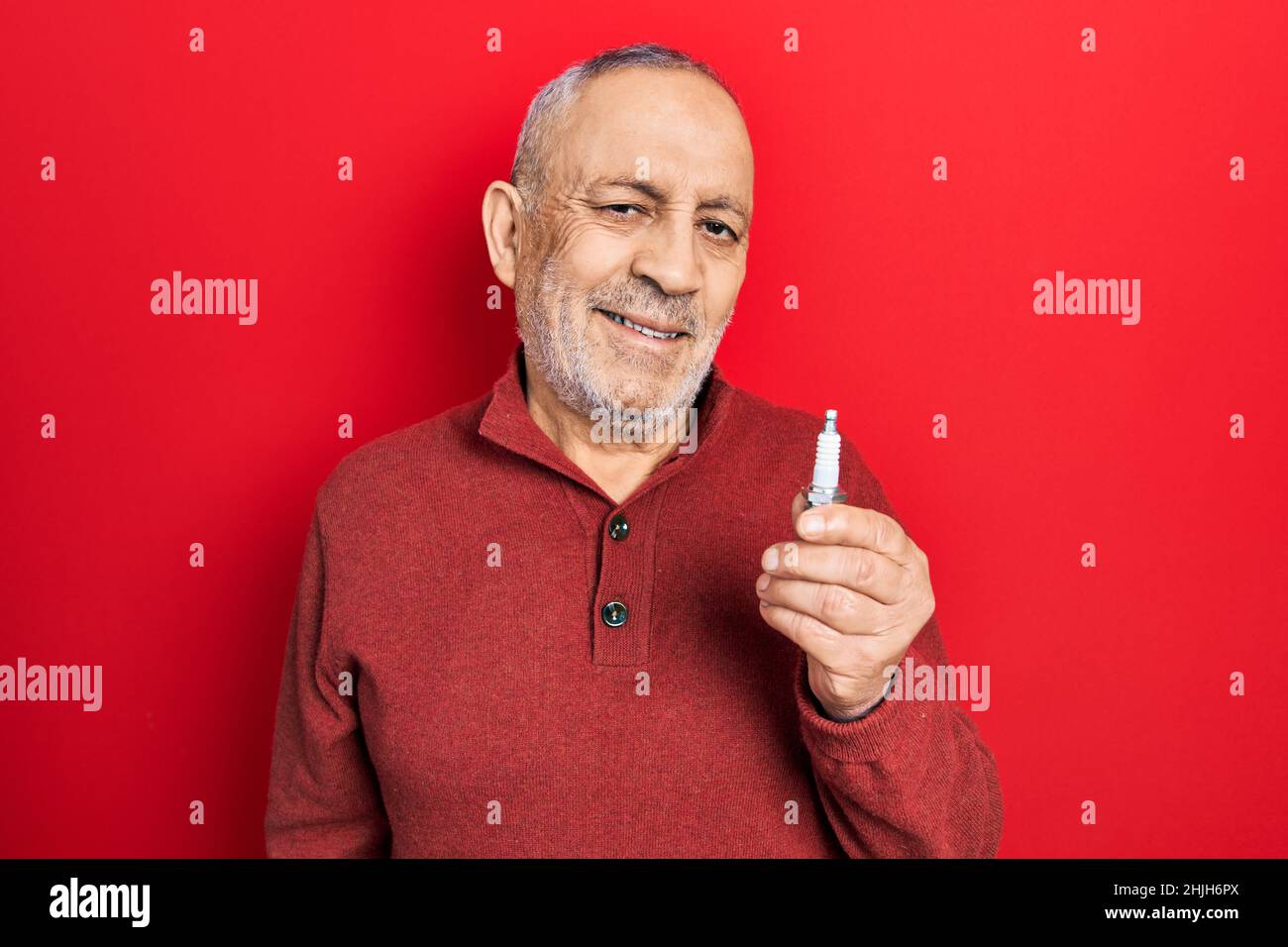 Handsome mature man holding spark plug looking positive and happy ...