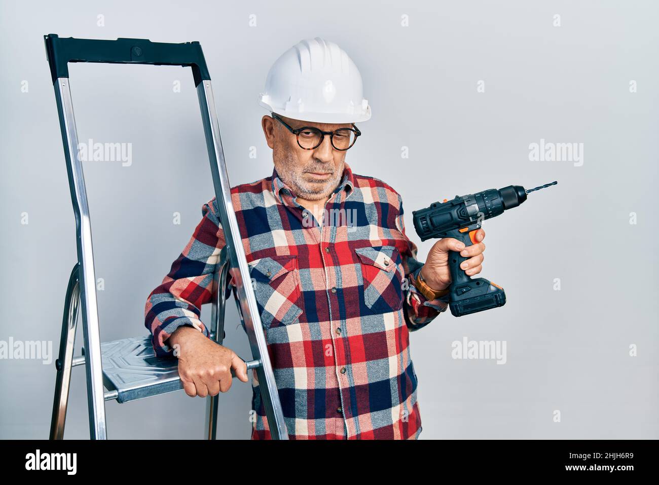 Handsome mature handyman holding screwdriver wearing hardhat by ...