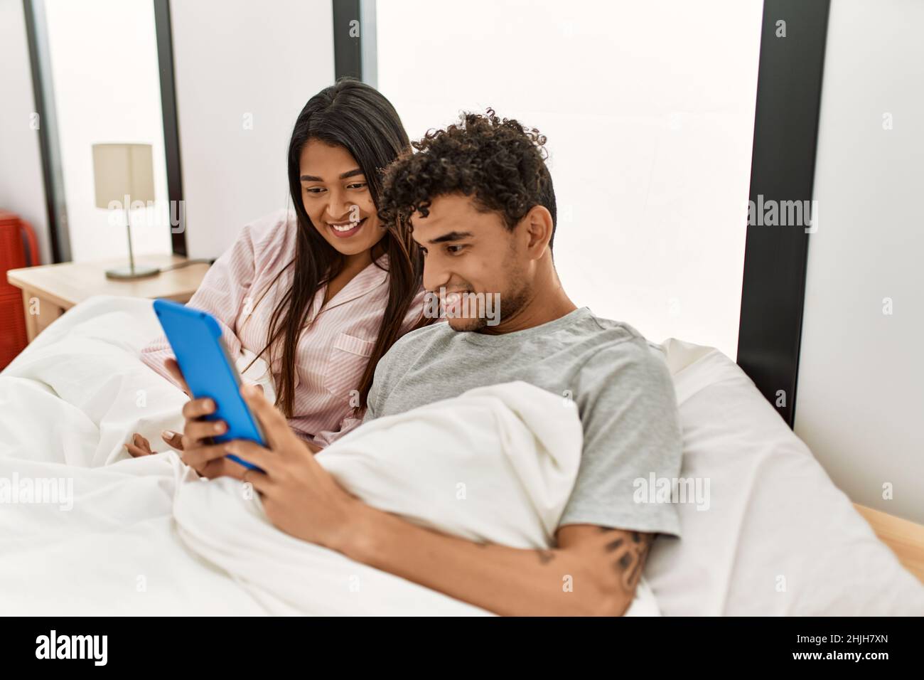 Young latin couple smiling happy using touchpad lying on the bed at bedroom Stock Photo - Alamy