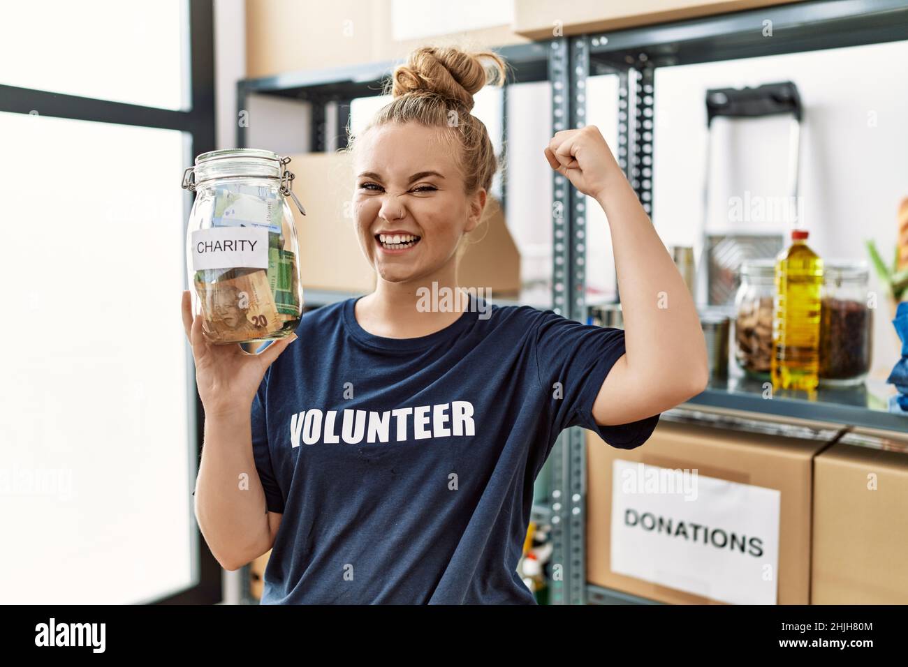 Young caucasian woman holding charity jar with money at donations stand ...