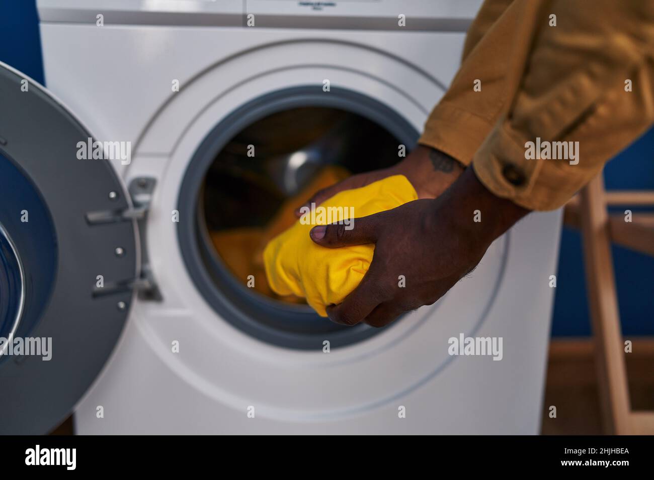 Young african american man washing clothes at laundry room Stock Photo ...