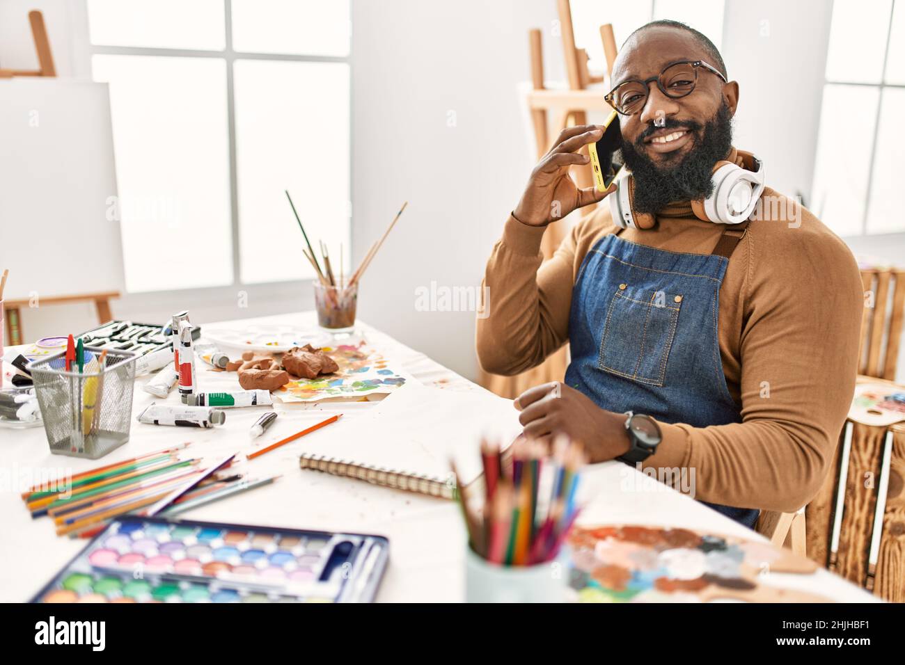 Young african american artist man using headphones and talking on the ...