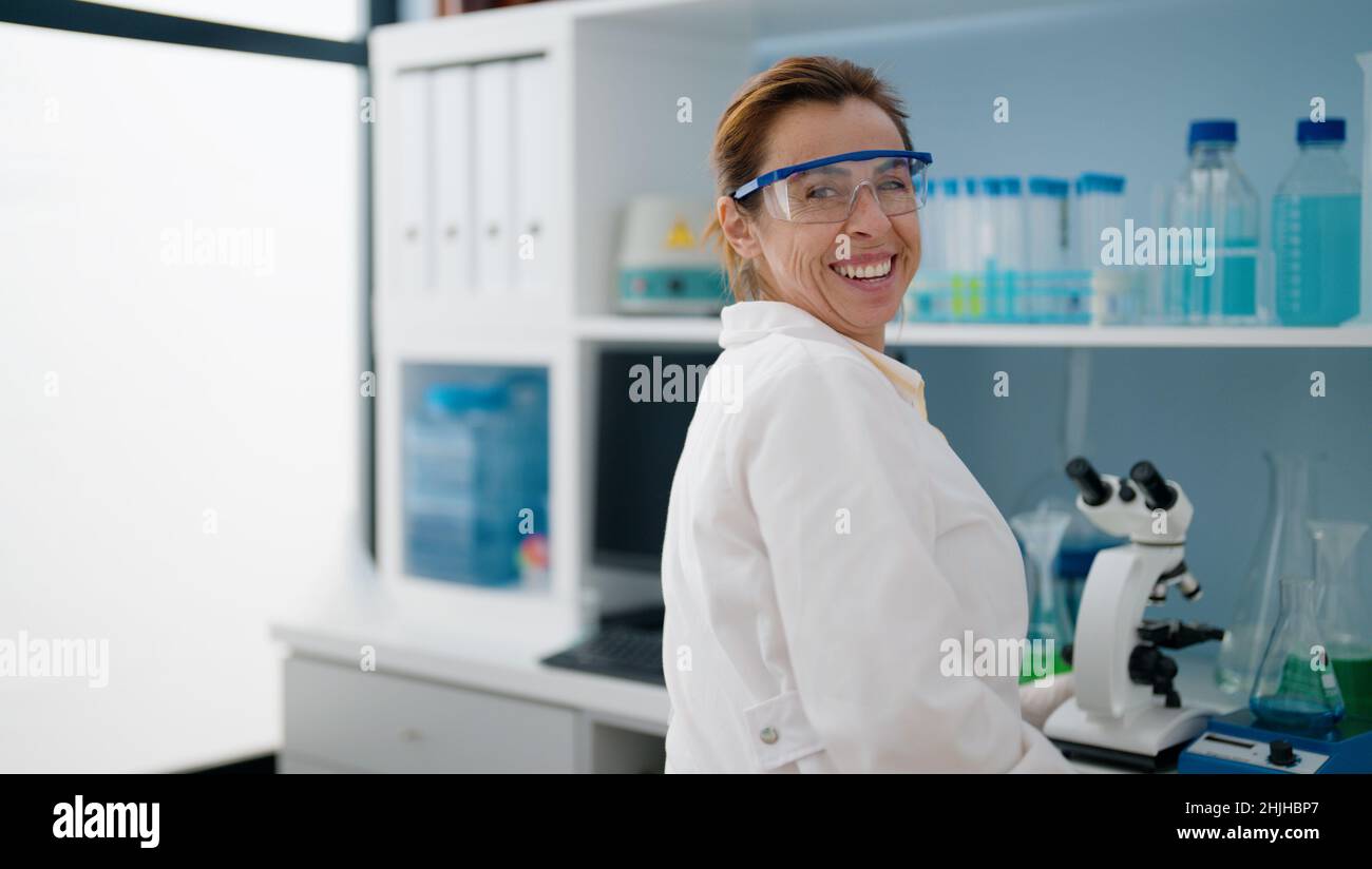 Middle age hispanic woman wearing scientist uniform standing at ...