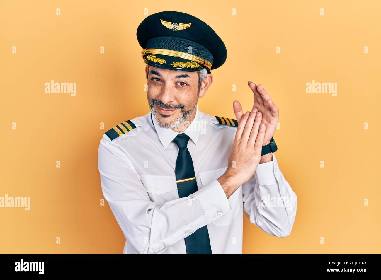 Handsome middle age man with grey hair wearing airplane pilot uniform ...