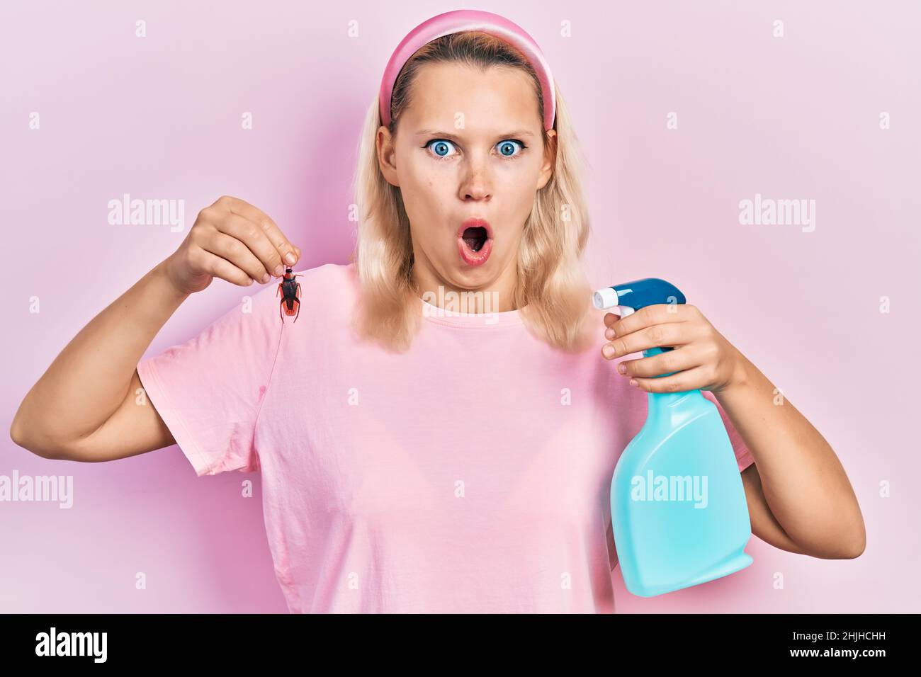 Beautiful caucasian blonde woman holding cockroach and pesticide ...