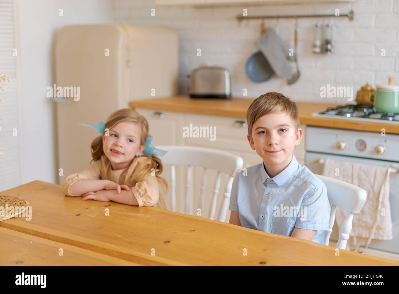 Children sit at table in kitchen and wait for their parents to make ...