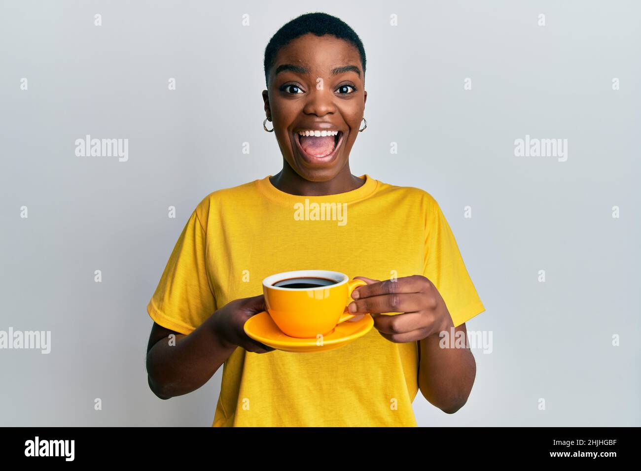 Young african american woman holding coffee celebrating crazy and ...