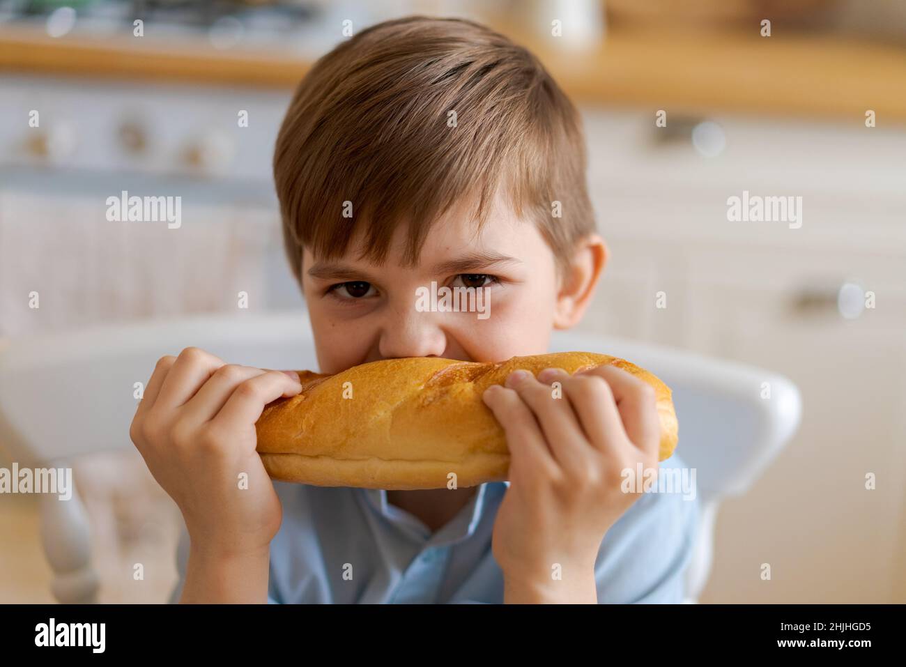 Happy handsome young teenage boy holding and eating freshly baked bread ...