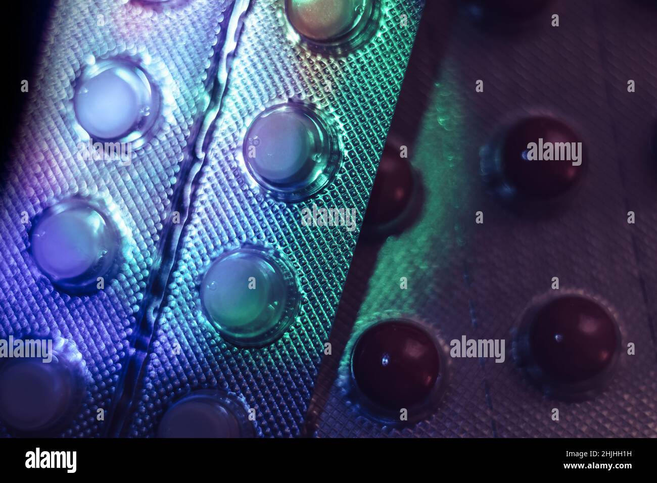 Pills or drugs in a package under neon light on a dark background ...