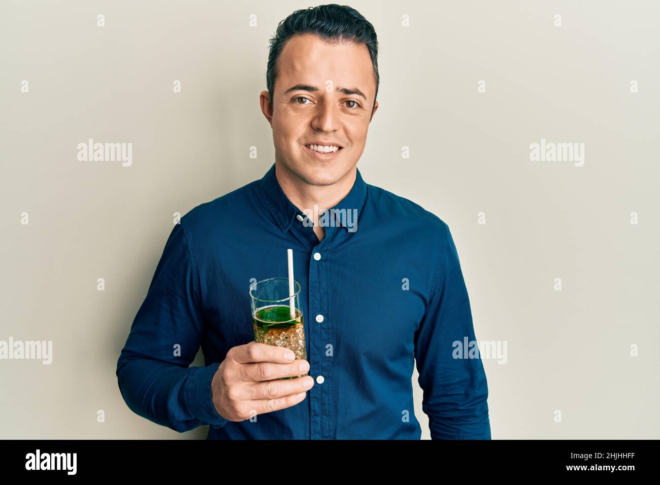 Handsome young man drinking mojito glass looking positive and happy ...