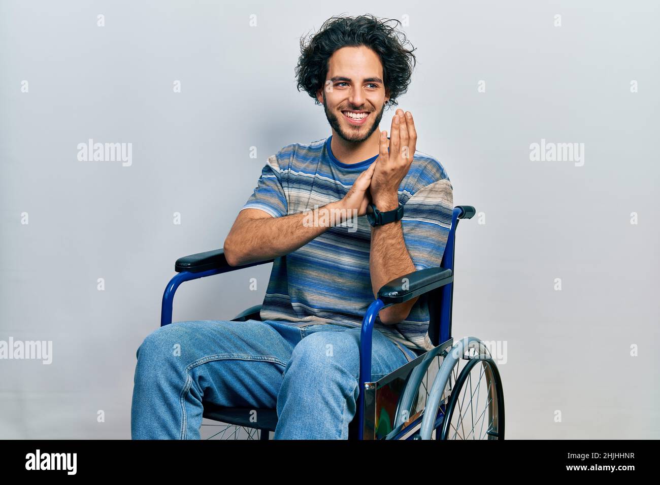 Handsome hispanic man sitting on wheelchair clapping and applauding ...