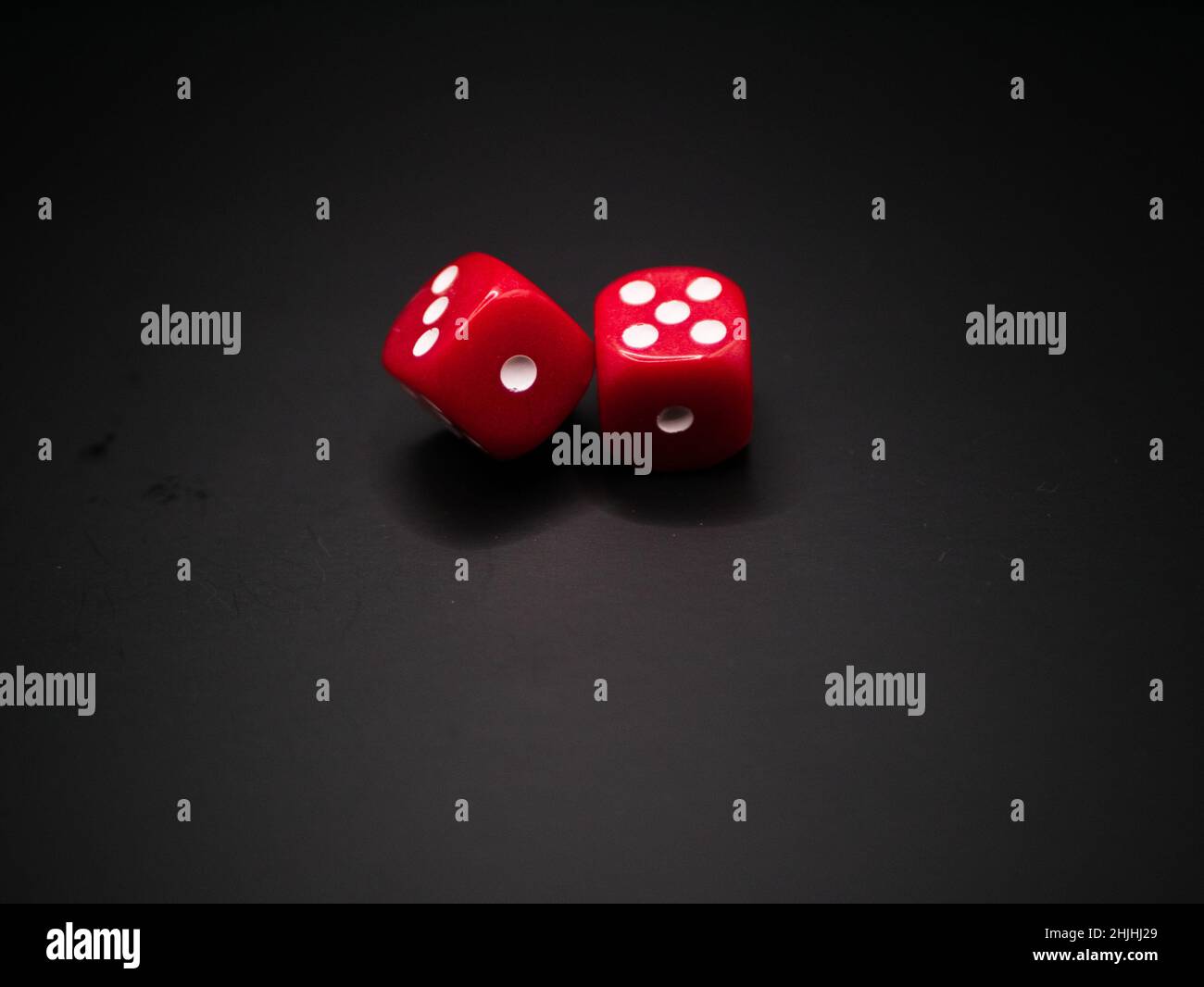 Two red dice on black background.close up with light source from above ...