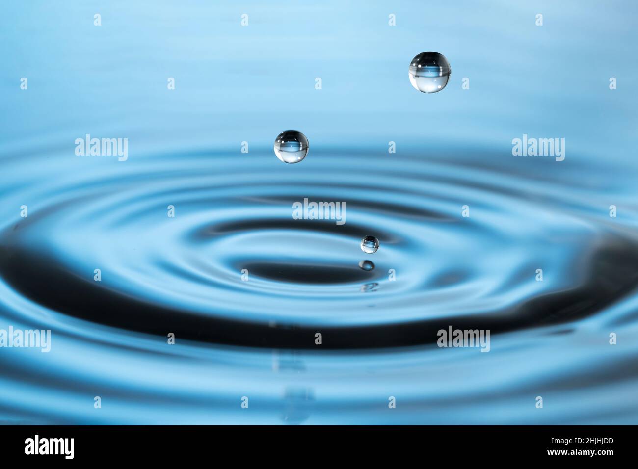Drops of water falling on smooth wet surface. Blue blurred background ...