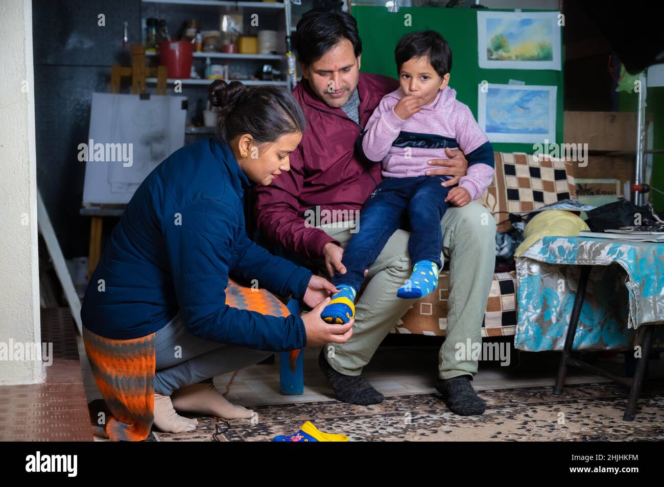 parents lovely their child to make shoes before going to play , this is ...