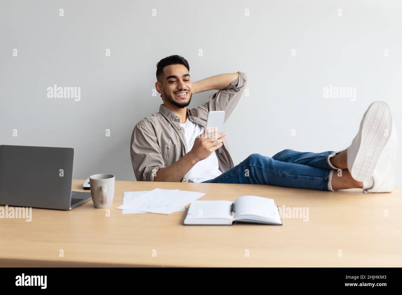 Arab man resting feet on table using mobile phone Stock Photo - Alamy