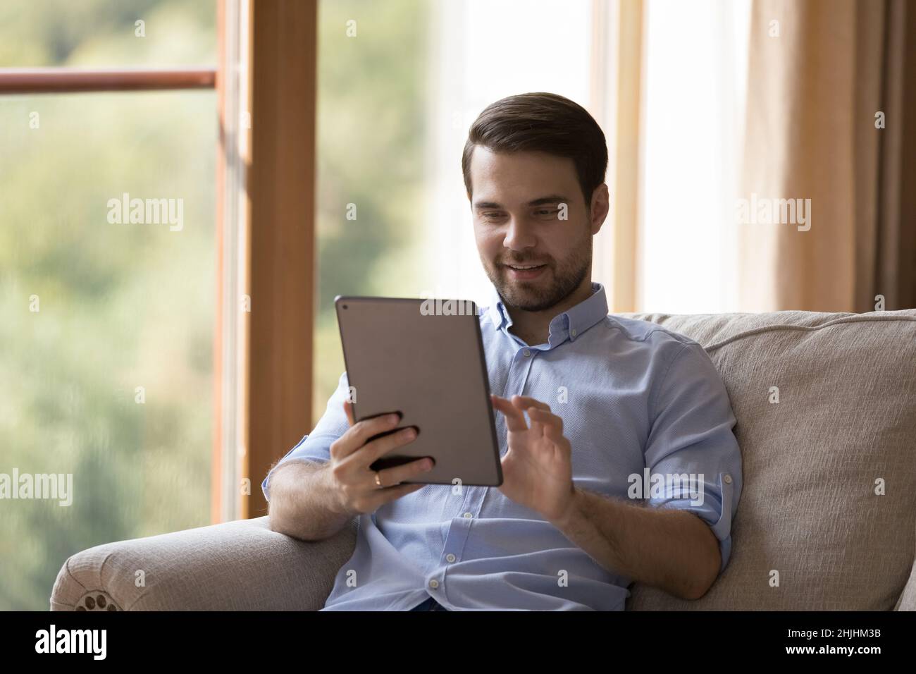Joyful millennial man using digital computer tablet Stock Photo - Alamy