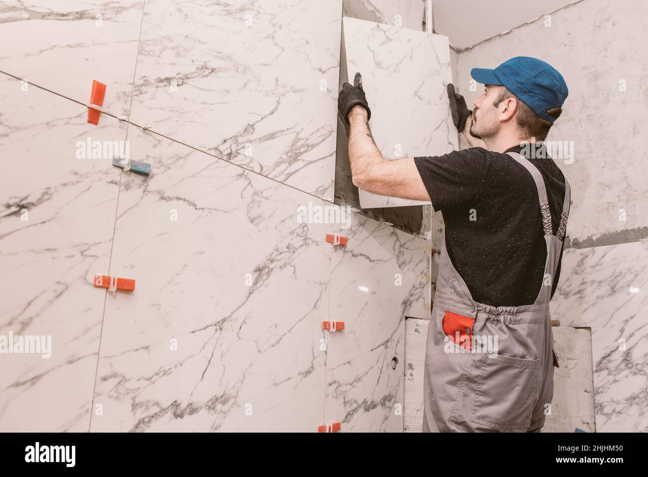 Handyman instaling ceramic tiles on the bathroom wall Stock Photo - Alamy