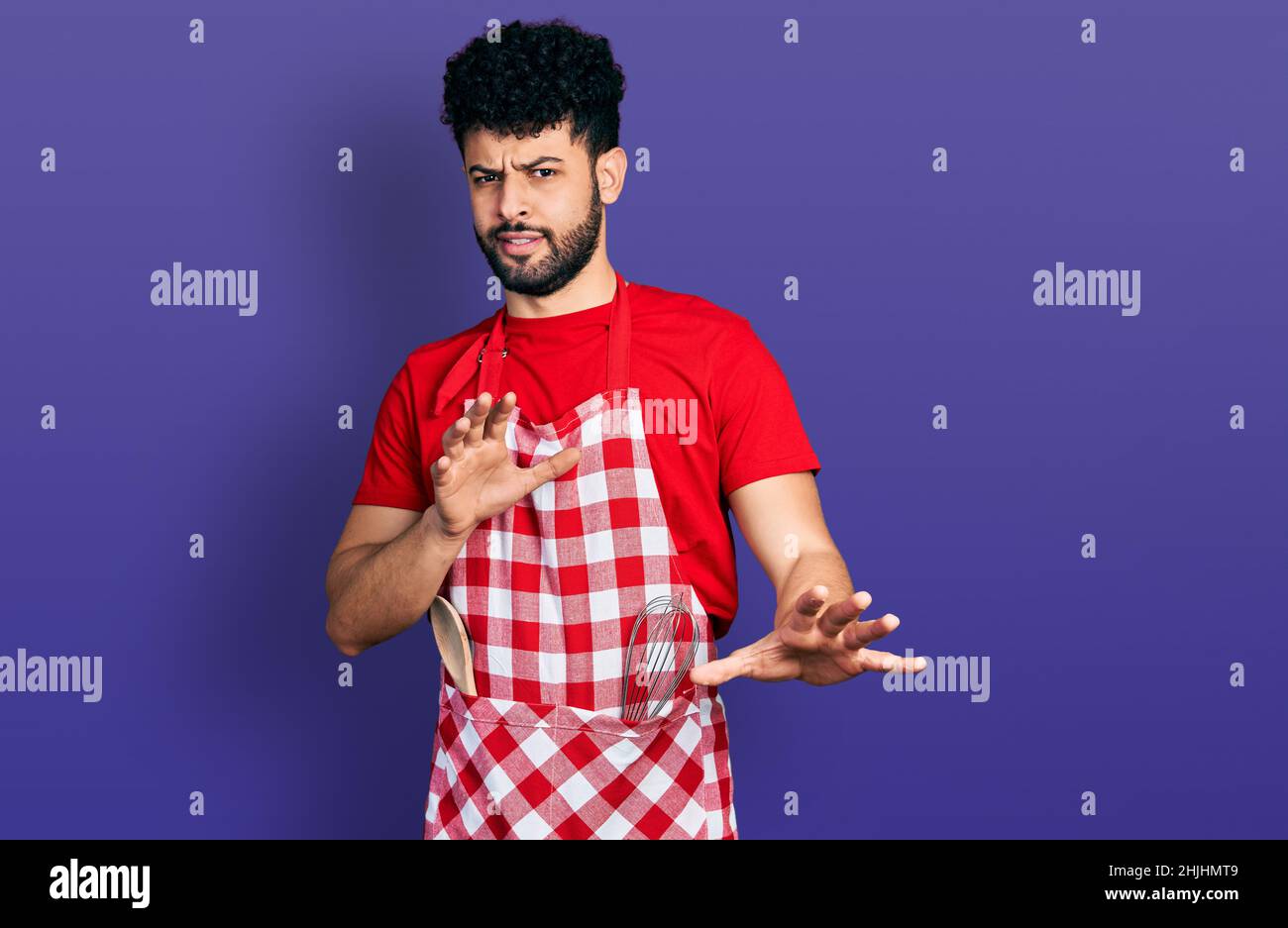 Young arab man with beard wearing cook apron disgusted expression ...