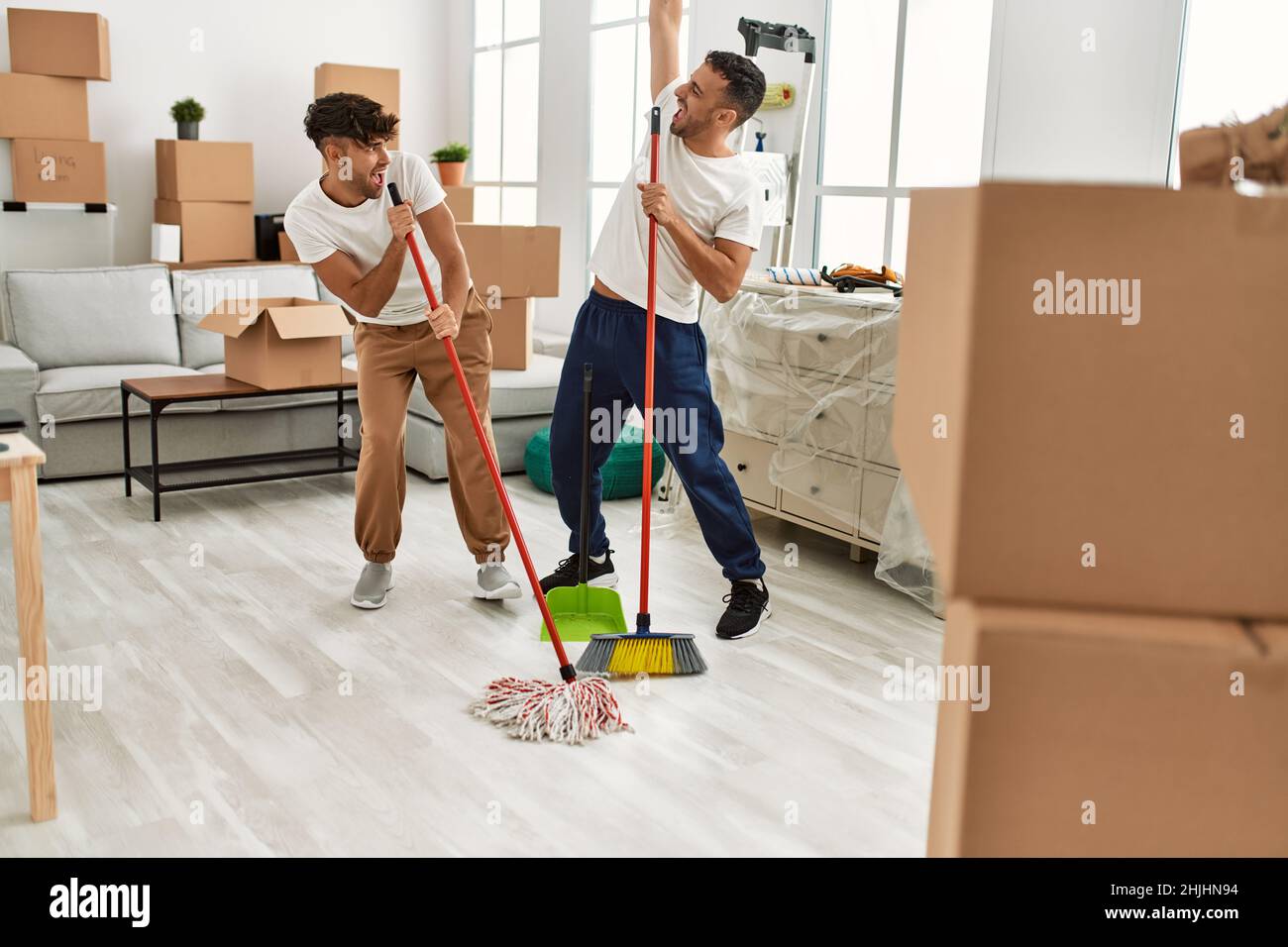 Two hispanic men couple cleaning and dancing at new home Stock Photo ...