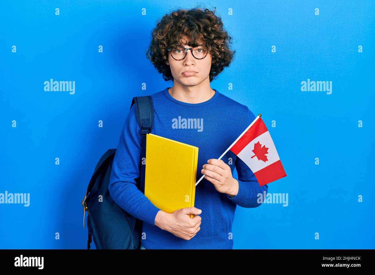 Handsome young man exchange student holding canada flag depressed and ...