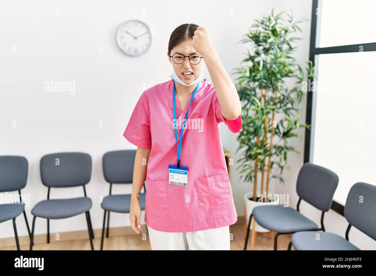 Young asian nurse woman at medical waiting room angry and mad raising ...