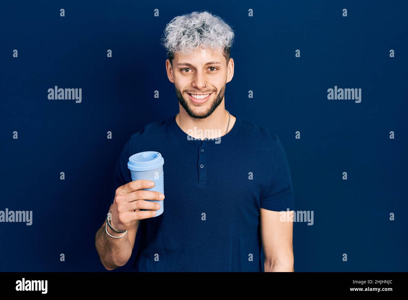 Young hispanic man with modern dyed hair drinking a take away cup of ...