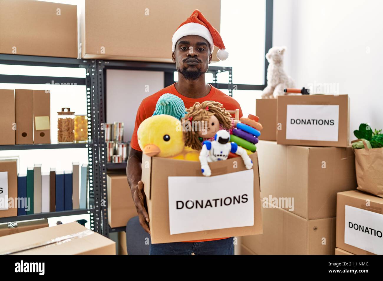 Young african man wearing volunteer t shirt and christmas hat holding ...