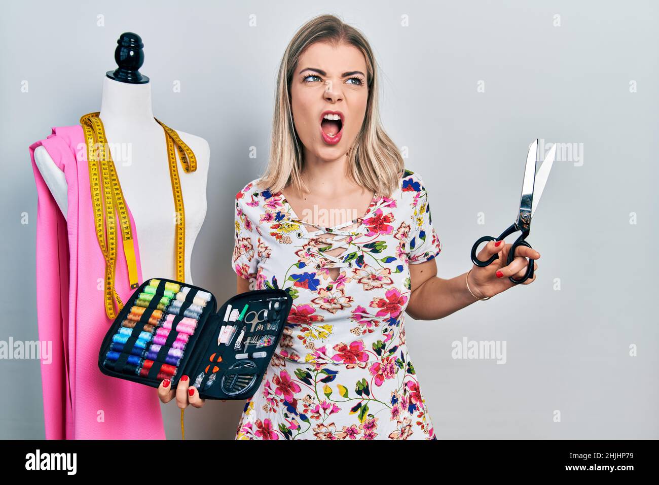 Beautiful caucasian woman dressmaker designer holding scissors and ...