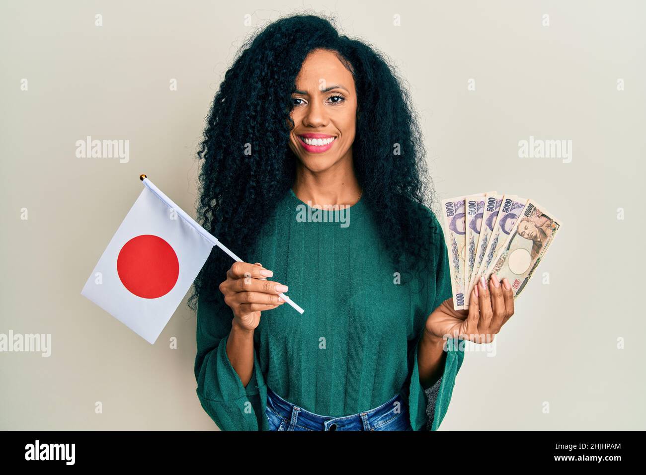 Middle age african american woman holding japan flag and yen banknotes ...