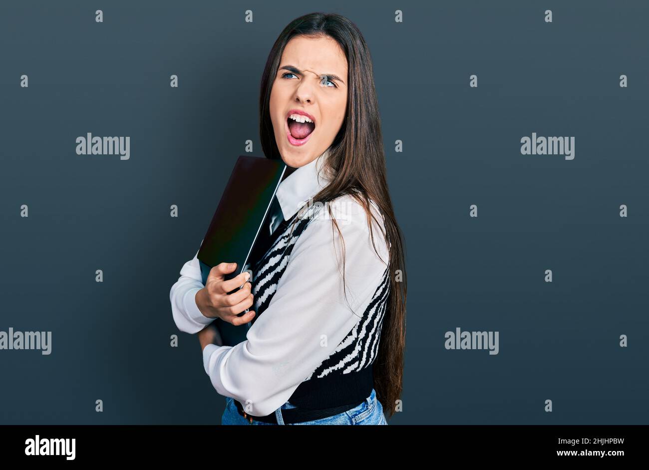 Young brunette teenager hugging laptop with love angry and mad ...