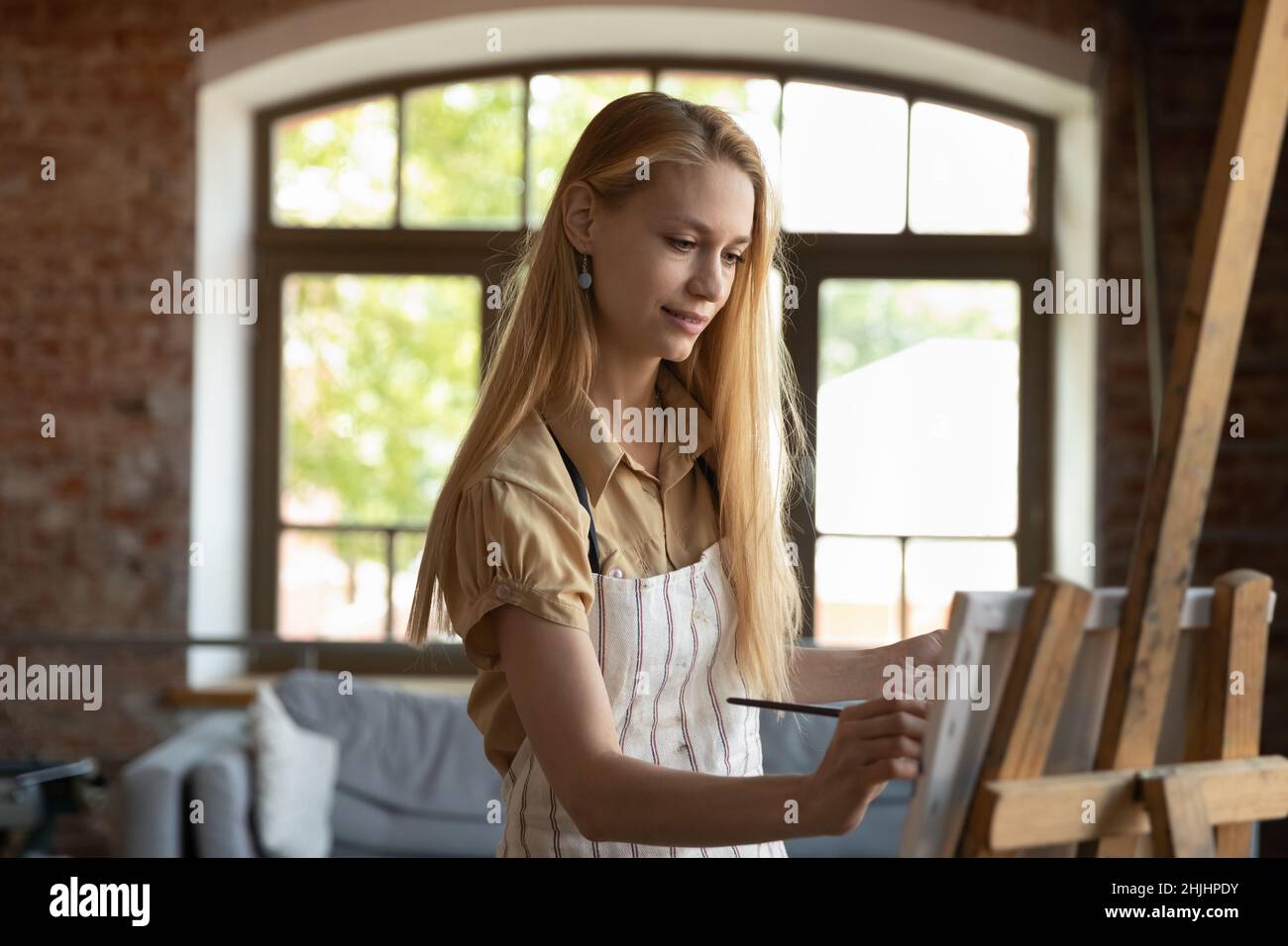 Focused positive artist girl enjoying creative work, painting picture ...