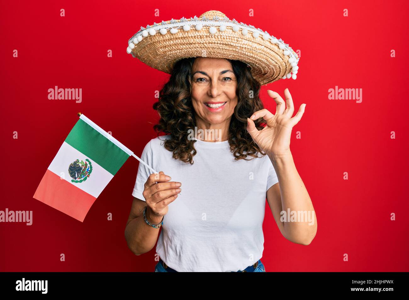 Middle age hispanic woman wearing mexican hat holding mexico flag doing ...