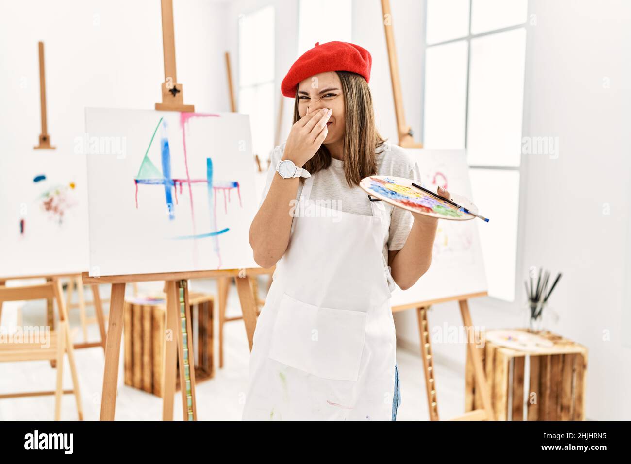 Young artist woman painting on a canvas at art studio smelling ...